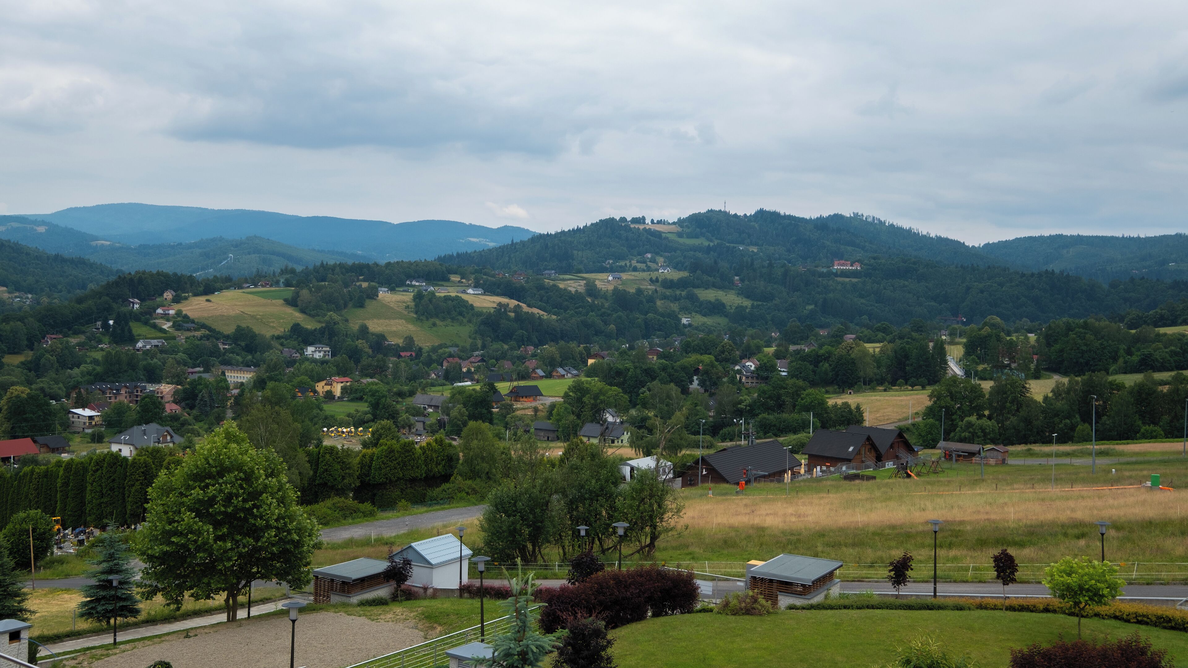 Uma vila rural com casas, um parquinho e uma estrada.