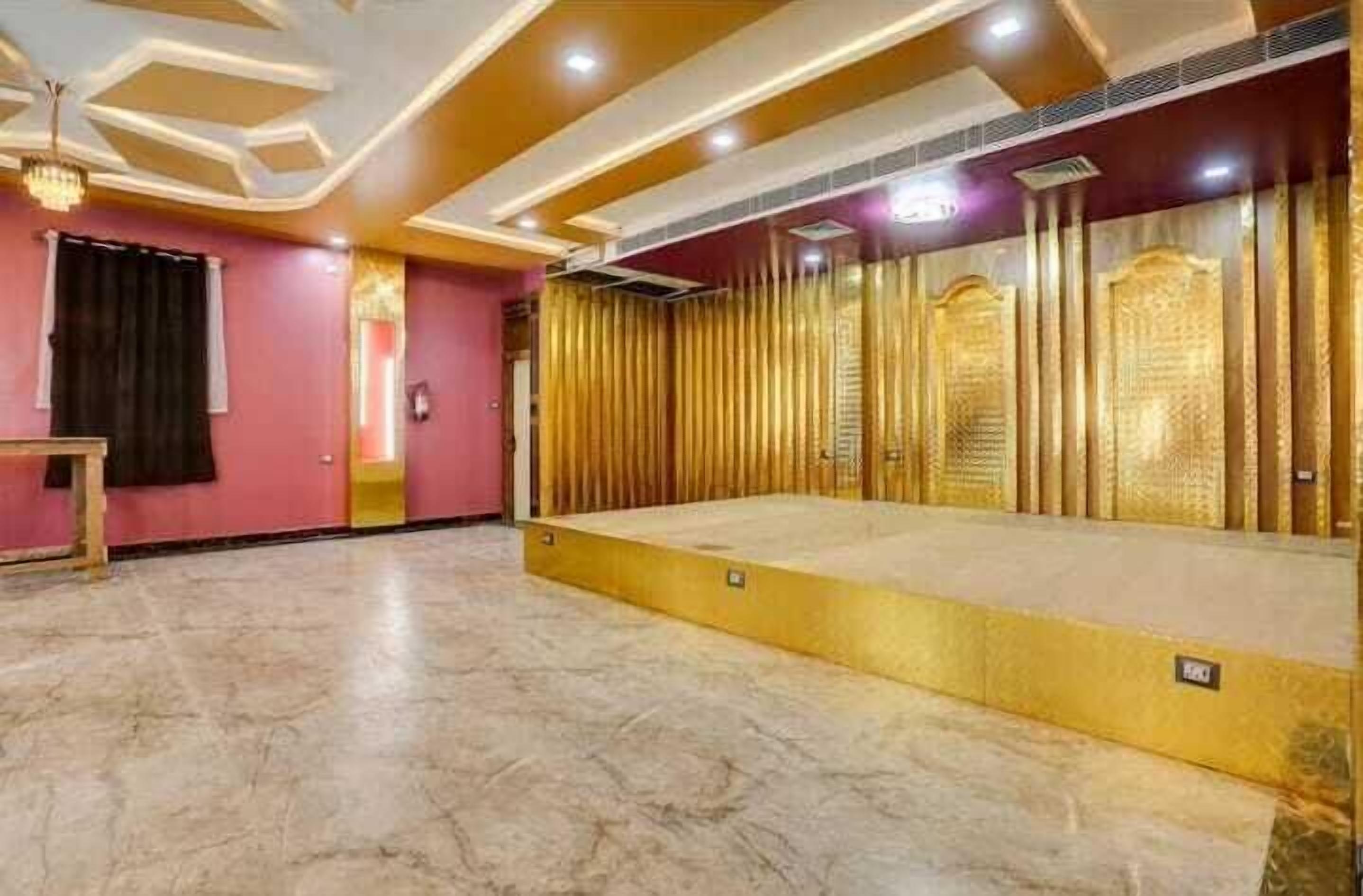Um quarto amplo com palco, lustre e parede estampada.