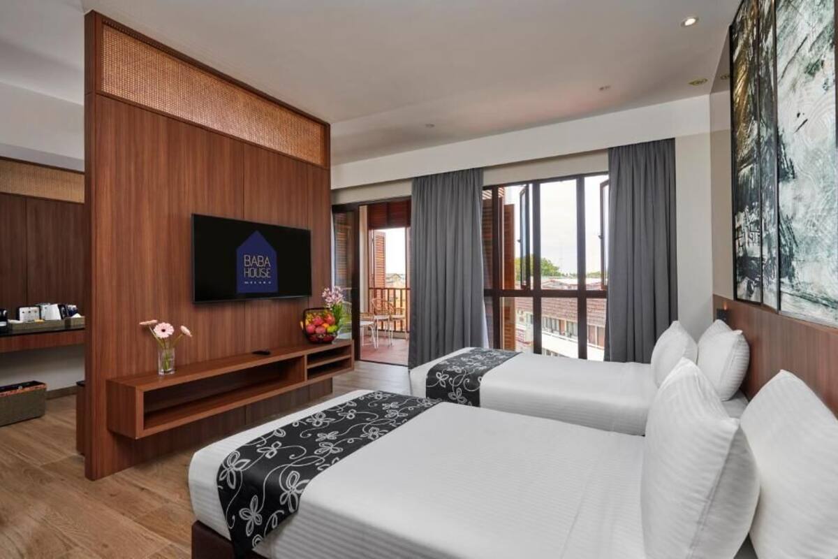 Quarto de hotel com duas camas, televisão, varanda com vista e um quadro abstrato grande.