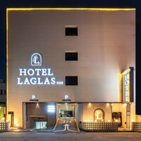Entrada de hotel com uma placa indicando 'HOTEL LAGLAS' e sinalização de estacionamento com a letra 'P'.