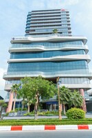 Um edifício de vários andares com design moderno, apresentando uma praça de entrada central e uma placa visível indicando que se trata de um hotel.