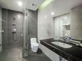 Uma casa de banho moderna com chuveiro em cabine de vidro, sanita e lavatório com espelho grande.