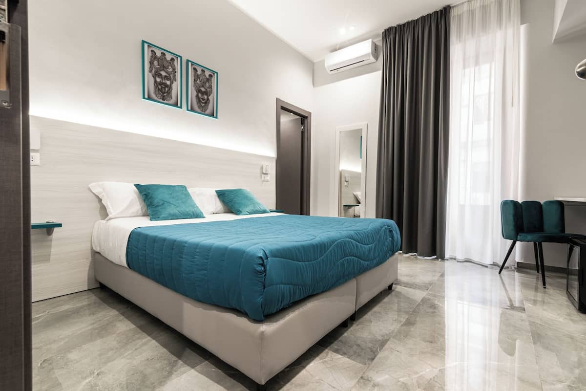 Quarto de hotel moderno com uma cama grande, uma escrivaninha e uma cadeira.