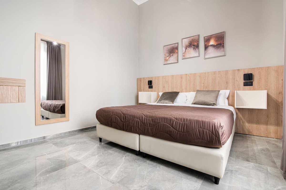 Quarto moderno com uma cama grande, cabeceira de madeira, luminárias de cabeceira e arte abstrata na parede.
