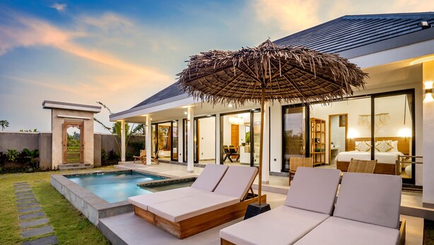 Uma casa moderna com piscina, cadeiras de descanso e um grande guarda-sol.