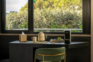 Uma mesa com um estojo de lenços, uma caneca, uma cafeteira Smeg e uma caixa de lenços.