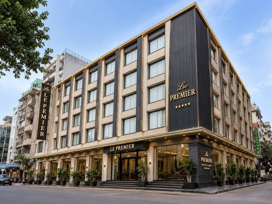 Hotel LE PREMIER, fachada moderna, vários andares e entrada imponente com degraus que levam ao saguão.