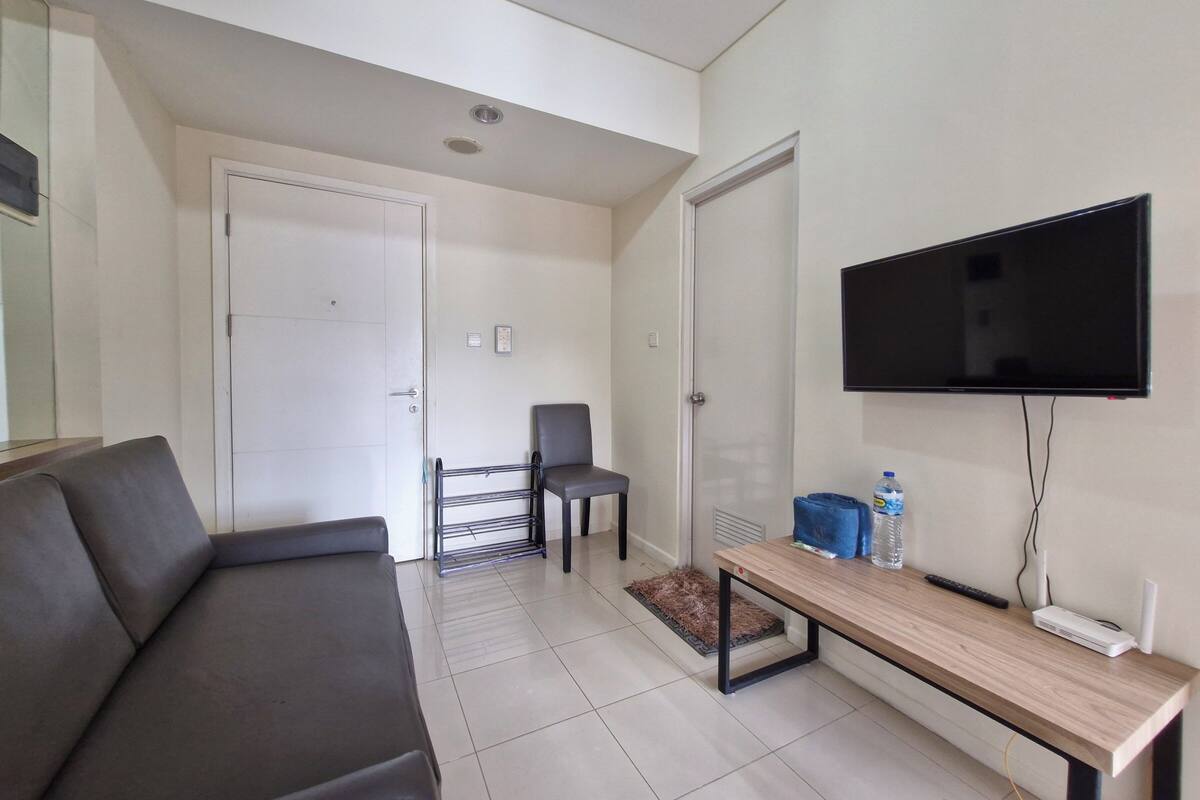 Uma sala de estar moderna com um sofá, uma mesa, uma televisão e uma porta que dá para outro quarto.