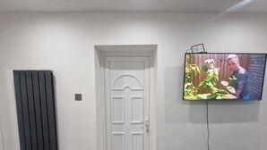 Quarto com porta branca, radiador e televisão presa à parede.