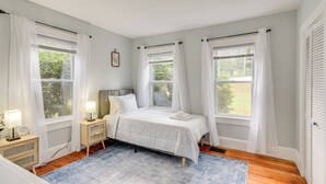 Quarto com cama, mesas de cabeceira e cortinas.
