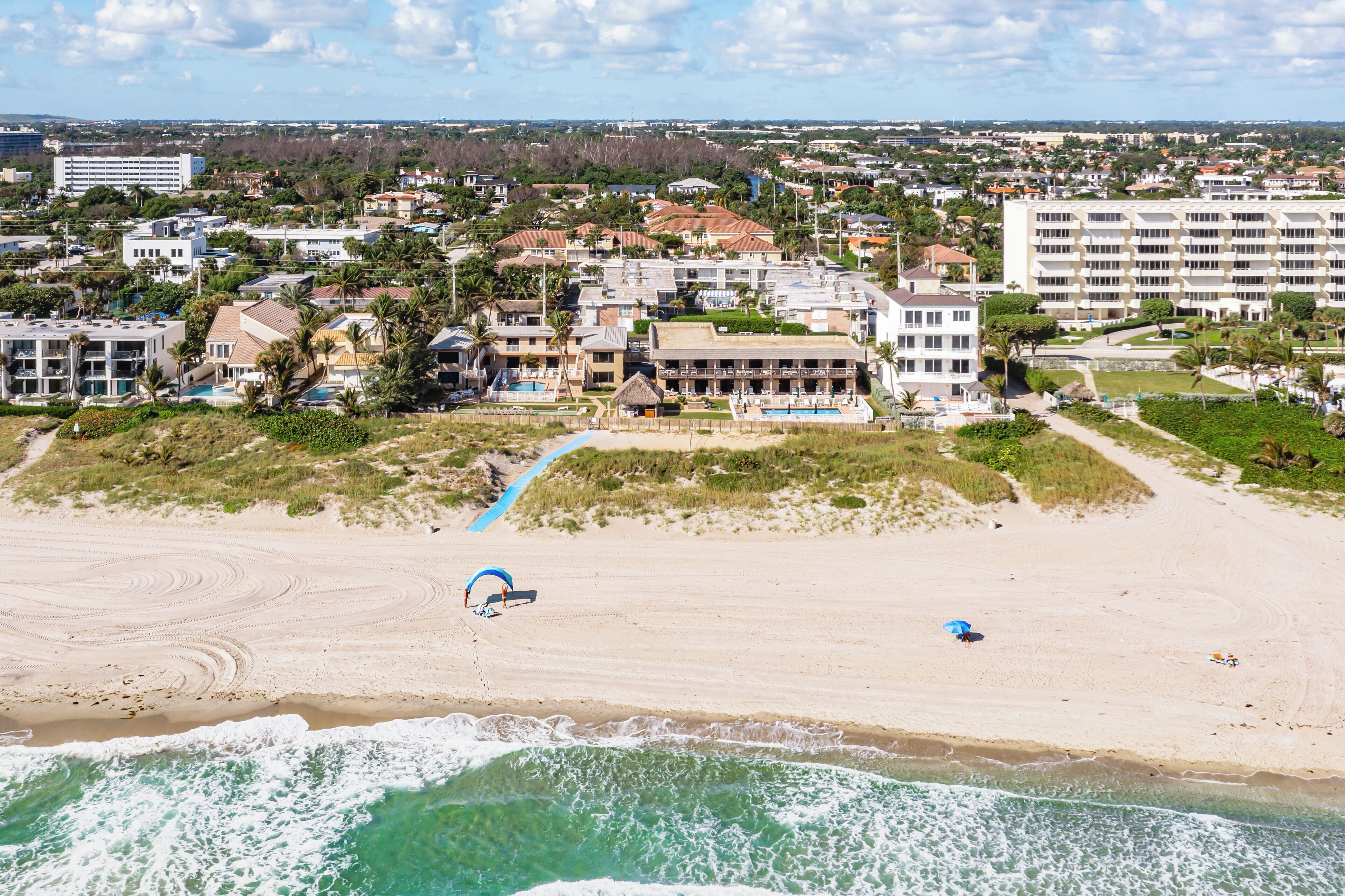 Um hotel à beira-mar com vários edifícios, uma praia e vista para o oceano.