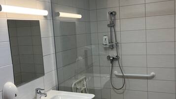 Um banheiro moderno com pia, espelho e chuveiro brancos.