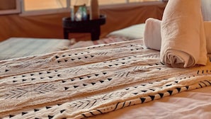 Uma tenda com cama, janela e vista para o deserto.