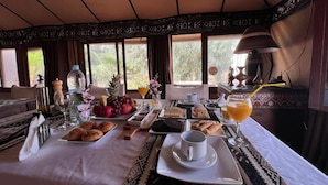 Uma mesa de café da manhã com diversos alimentos, uma xícara e um copo de suco de laranja.