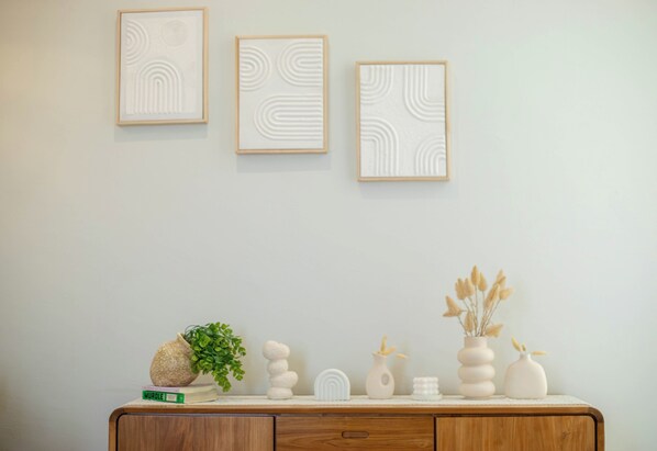 Quarto com um armário de madeira, uma planta e três quadros na parede.