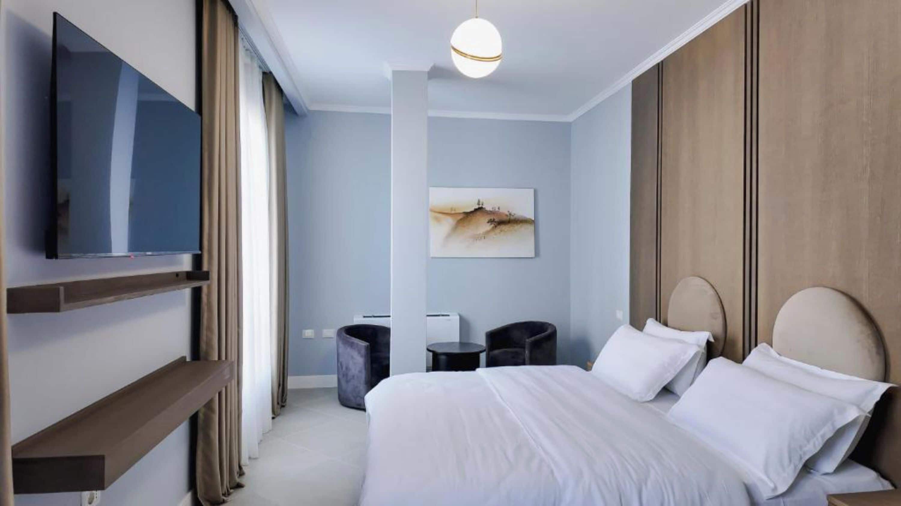 Quarto de hotel moderno com uma cama grande, uma televisão de tela plana, uma pintura na parede e um painel de madeira na parede.