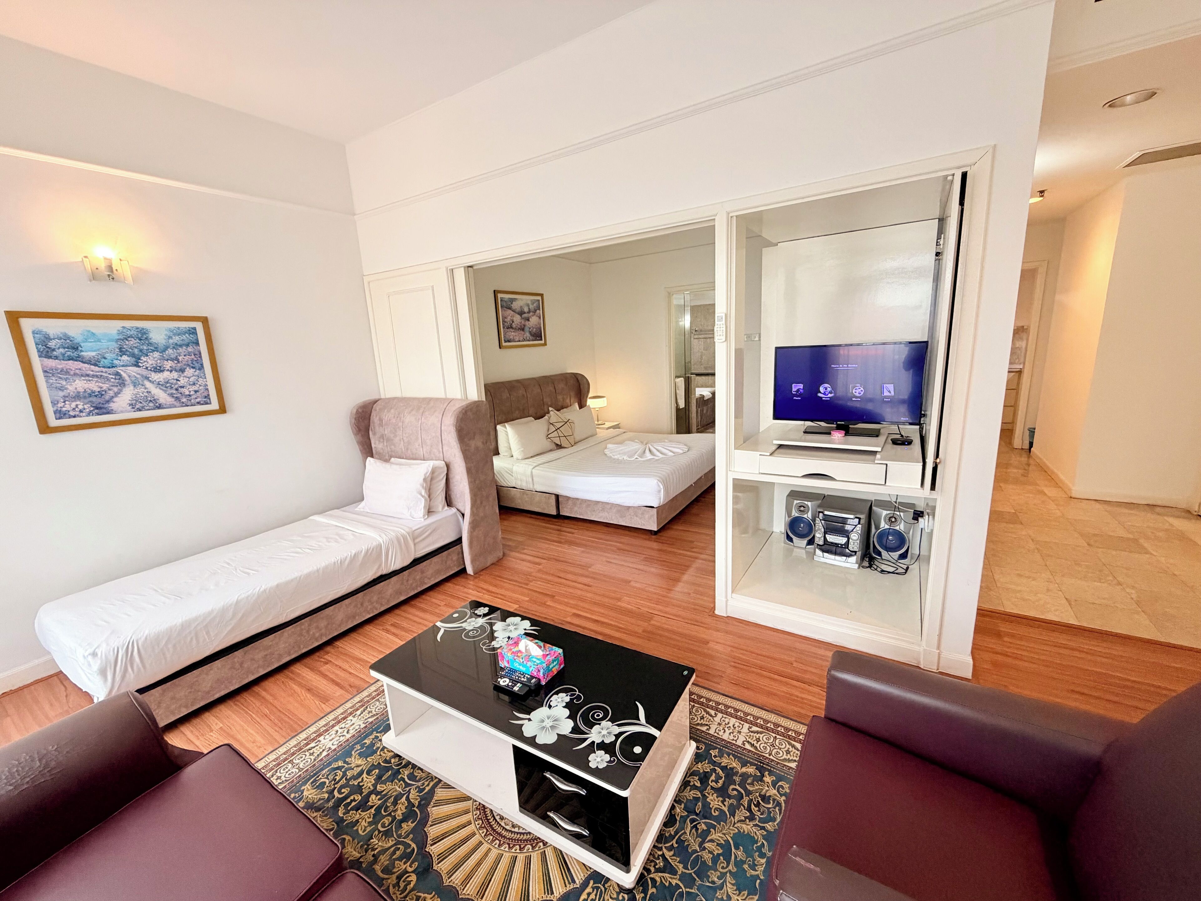 Uma sala de estar moderna com um sofá, uma mesa de centro, uma TV e uma cama.
