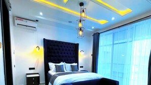 Quarto moderno com uma cama grande, uma mesa de cabeceira, um abajur e um candeeiro de chão.