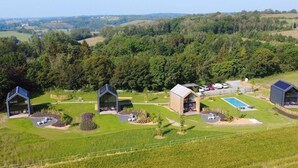 Um resort moderno e ecológico com várias cabanas, piscina e vegetação exuberante.