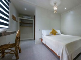 Um quarto com uma cama, uma cadeira, uma estante e um lustre.
