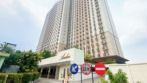 Um hotel alto com design moderno, com entrada destacada e várias varandas.