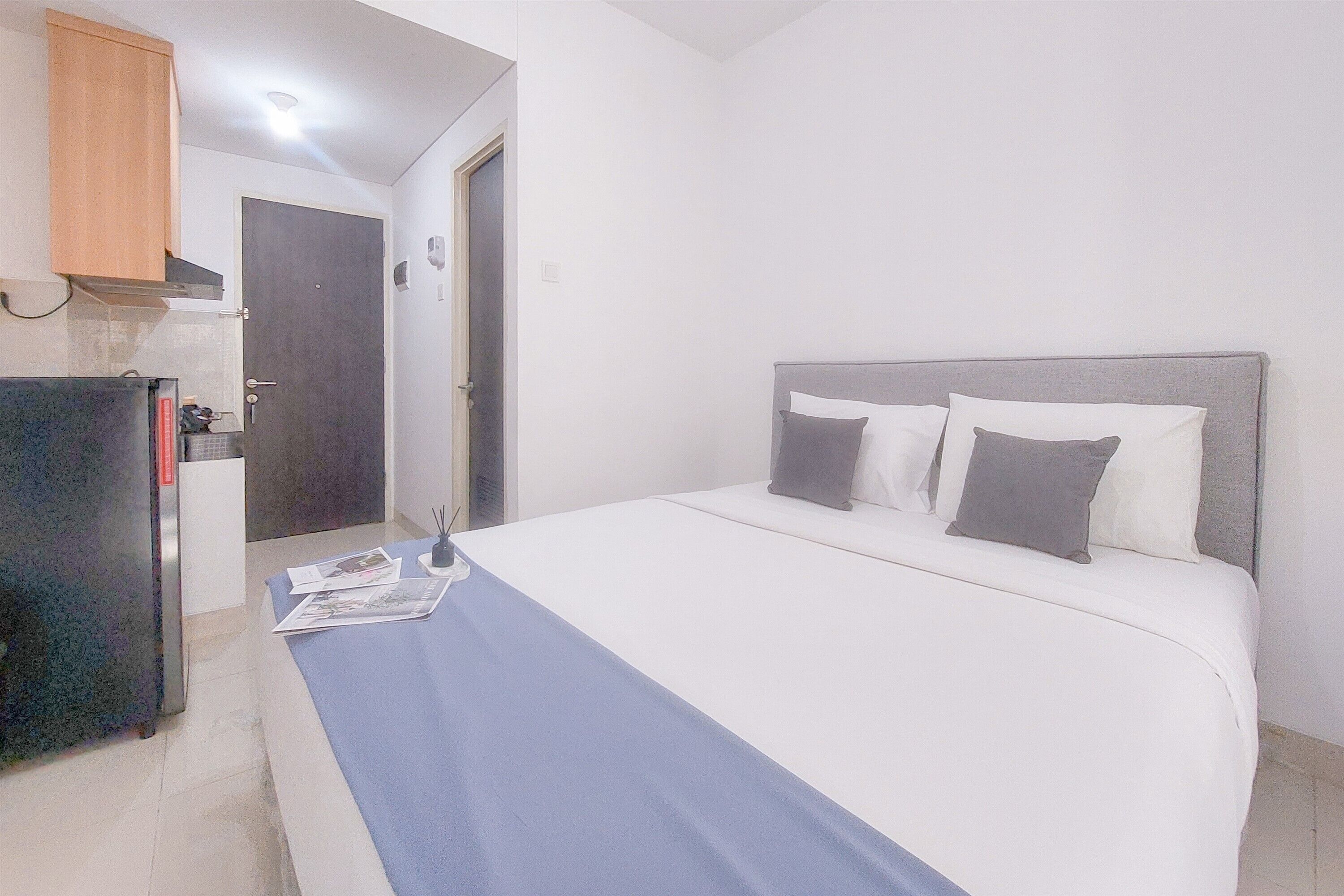 Um quarto com uma cama, escrivaninha e porta.