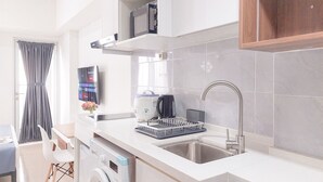 Cozinha moderna com máquina de lavar embutida, cafeteira e pia.