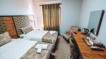 Quarto de hotel com duas camas, uma escrivaninha de madeira, uma cadeira, cafeteira e um espelho.