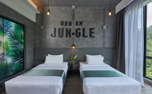 Quarto de hotel moderno com duas camas, uma janela grande com vista e uma parede com o texto "URBAN JUNGLE".