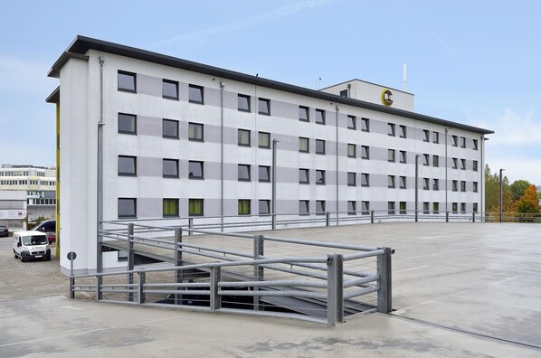 Um edifício moderno com telhado plano, várias janelas e portão.