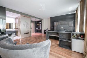 Quarto de hotel moderno com cozinha compacta, área de estar e closet espaçoso.