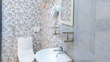 Casa de banho com parede revestida em azulejo, sanita, lavatório e espelho.