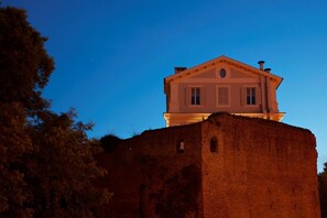 Um edifício com estilo arquitetônico clássico, apresentando uma fachada simétrica com frontão central e varanda.