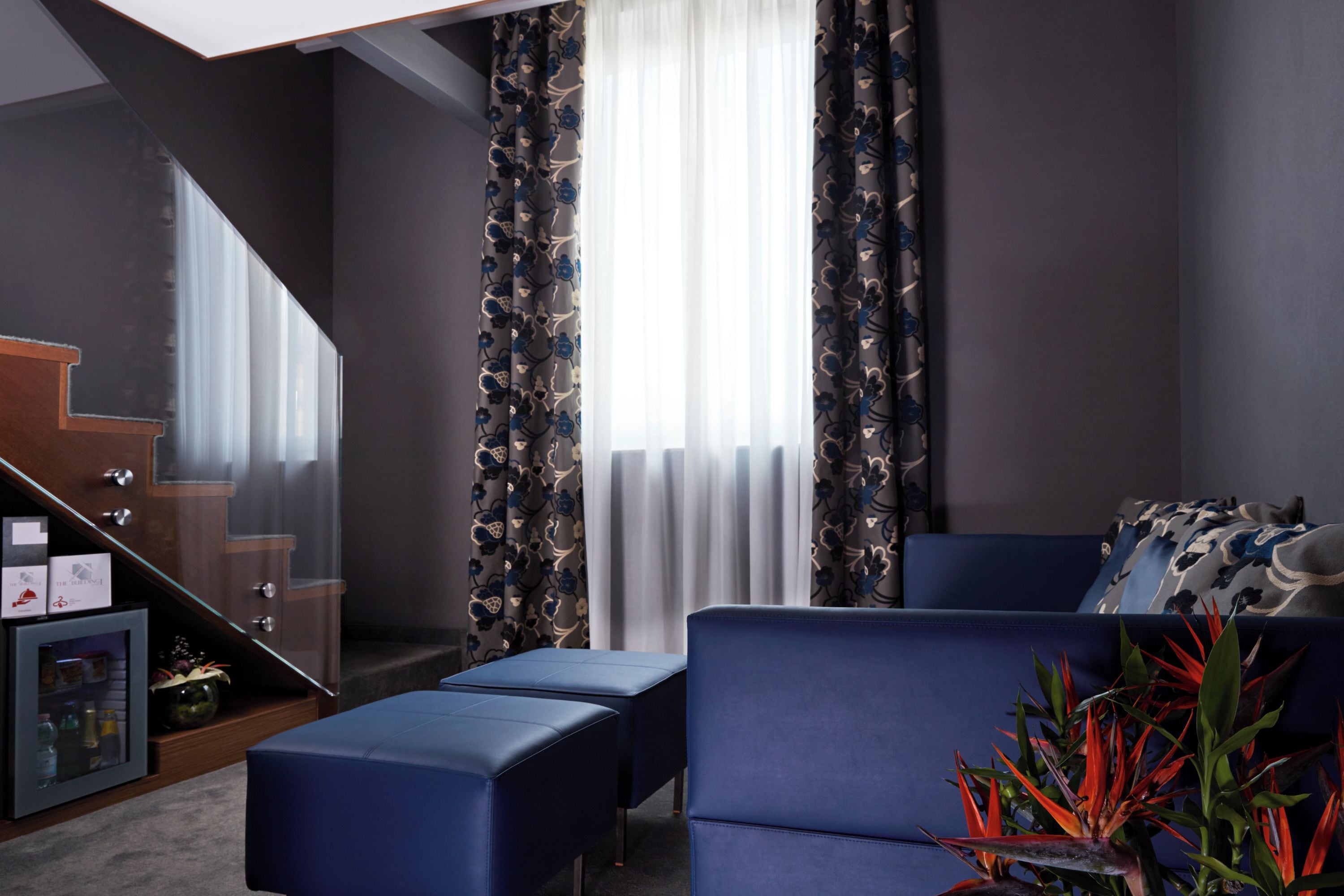 Uma sala de estar moderna com escada, sofá e planta decorativa.