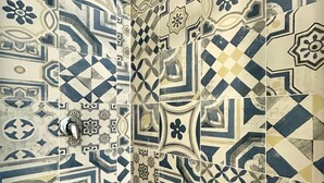 Casa de banho com parede revestida de azulejos com padrões geométricos e zona de duche com torneira moderna.