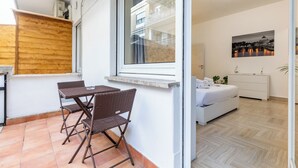 Um espaço compacto com área de jantar, sofá branco, cozinha pequena e grande janela com vista para um edifício.