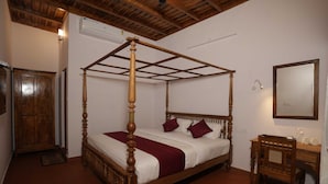 Uma cama de dossel com estrutura de madeira, uma mesa de cabeceira com espelho e um guarda-roupa.