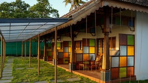 Uma casa tradicional com varanda coberta, área de estar com cadeiras e um caminho que leva à entrada.