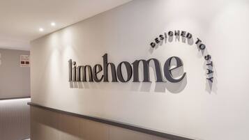 Paredes com as palavras “lighthouse home” e “DESIGNED TO STAY” numa fonte moderna.