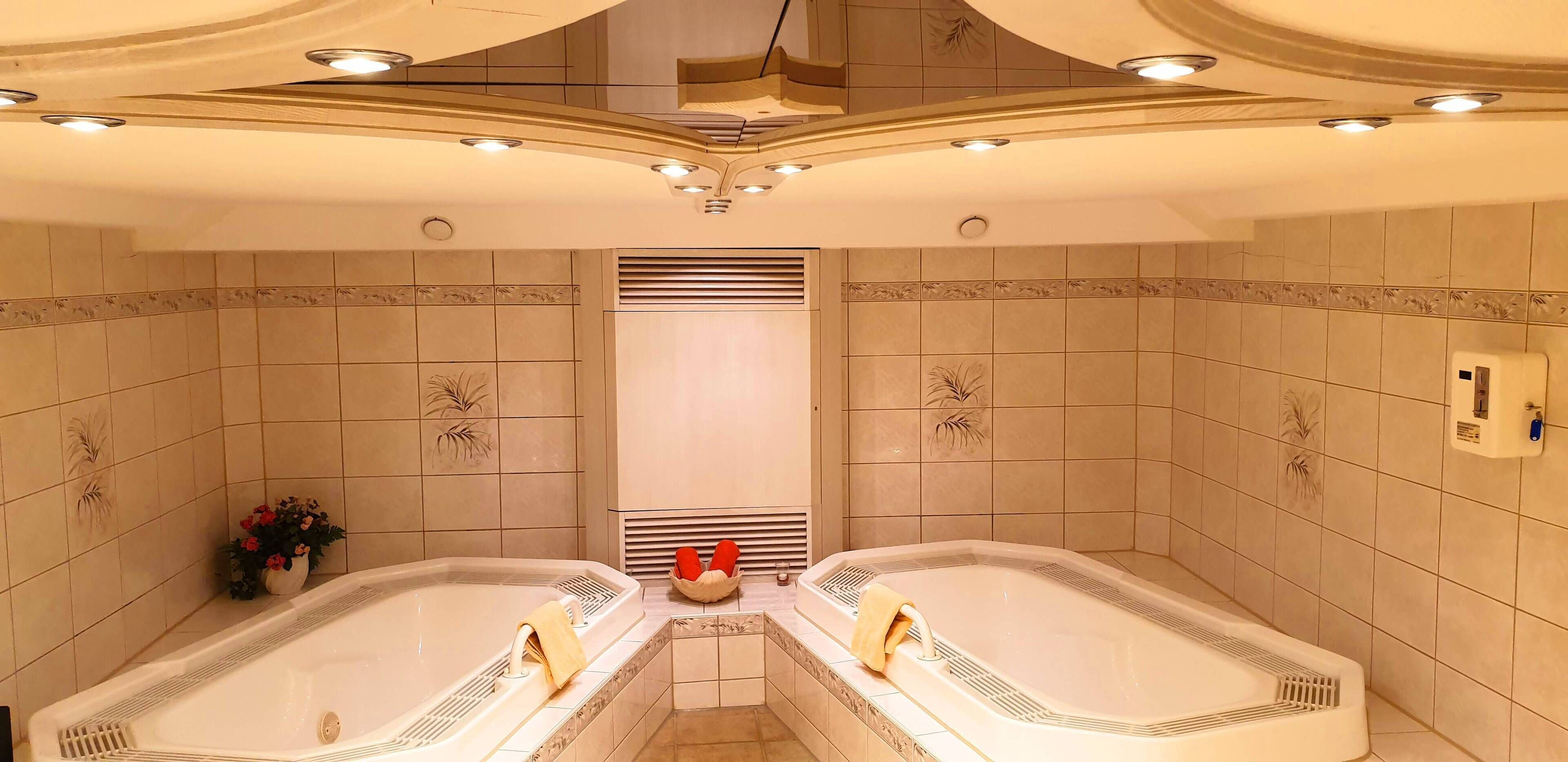 Um banheiro luxuoso com duas banheiras grandes, um painel decorativo e iluminação embutida no teto.