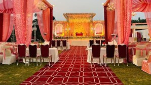 Espaço para eventos ao ar livre, com palco, tapete vermelho e fileiras de cadeiras.