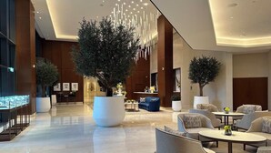 Um hall amplo com uma grande receção, área de estar e plantas decorativas.
