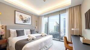 Quarto de hotel moderno com uma cama grande, uma escrivaninha e vista para a cidade.