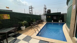 Uma área de piscina com piso xadrez, assentos e um aviso de proibido fumar.