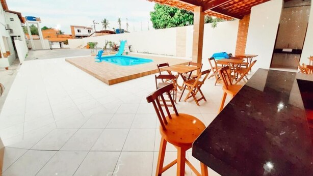 Um pátio externo com piscina, área de refeições e cozinha.