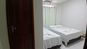 Quarto com duas camas de solteiro, porta de madeira e teto branco.