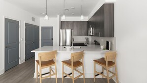 Cozinha moderna com ilha central, banquetas e geladeira.