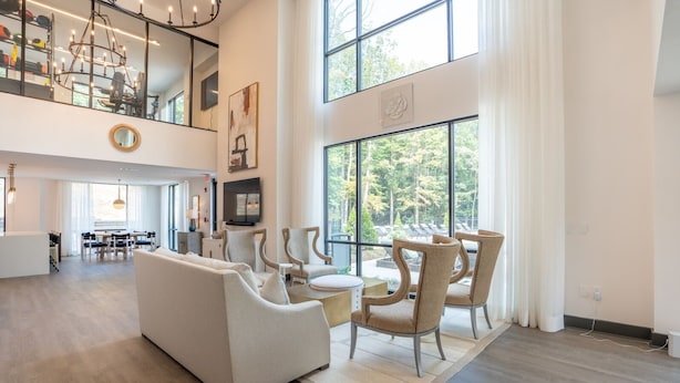 Uma sala ampla com sofá, cadeiras, mesa de jantar e uma grande janela com vista para o exterior.