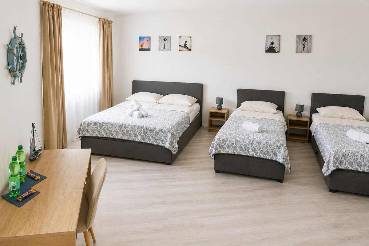 Quarto de hotel com duas camas, uma mesa de madeira e uma cadeira.