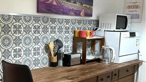 Cozinha com bancada de madeira, micro-ondas, torradeira e cafeteira.